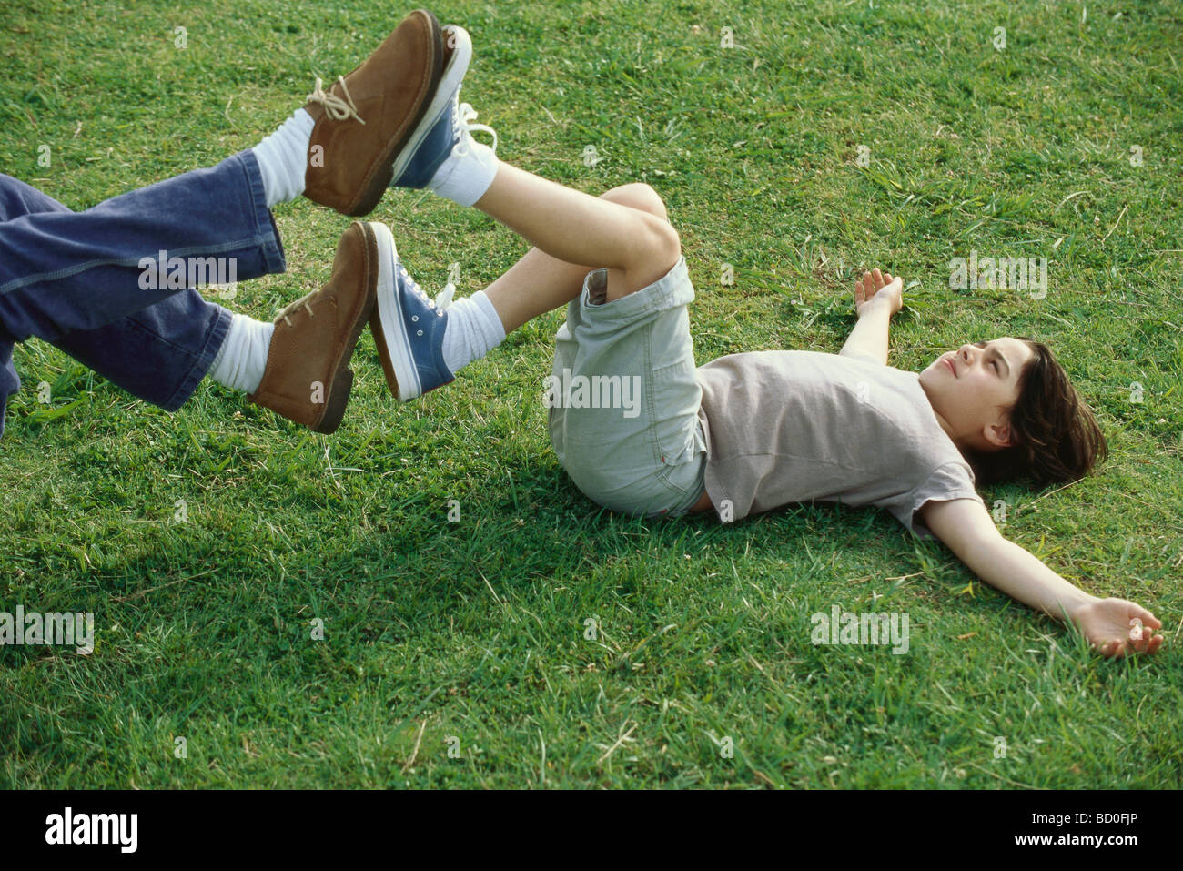 Boy lying on back in grass playing footsies with father Stock Photo - Alamy