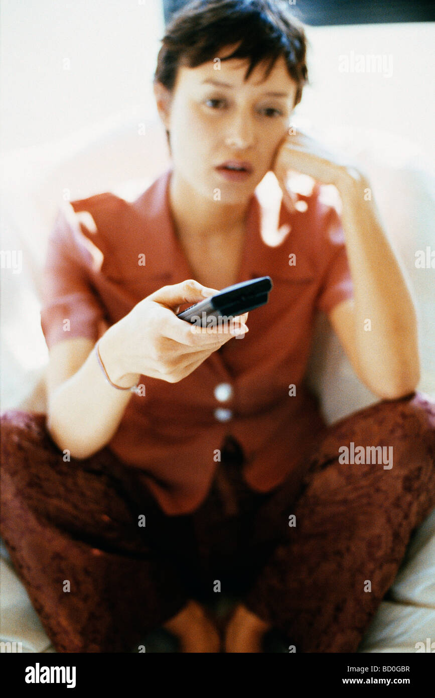 Woman holding remote control, dull expression on face Stock Photo - Alamy