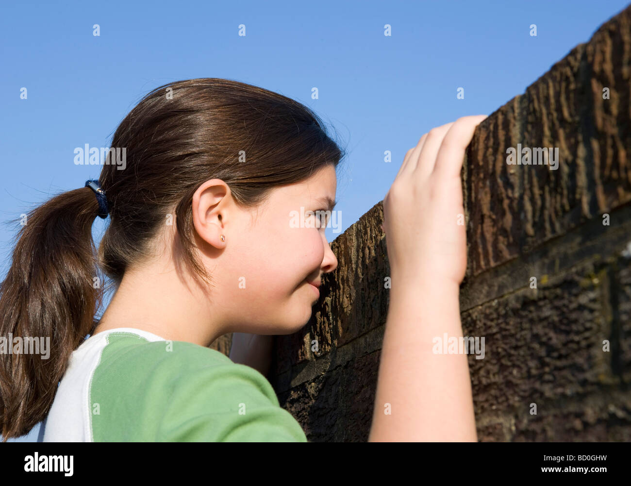 Girl looking over wall Stock Photo - Alamy
