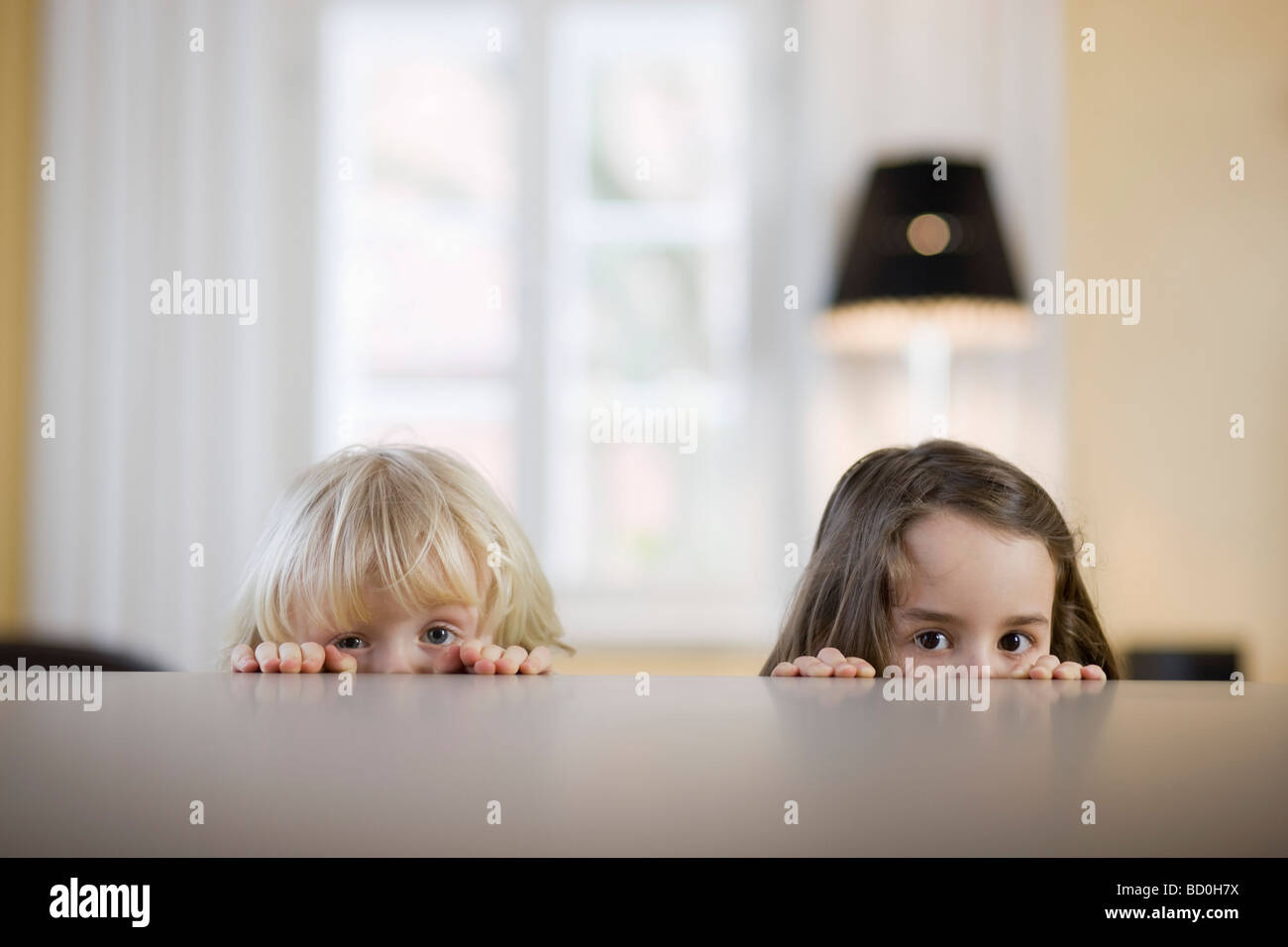 children looking over table edge Stock Photo - Alamy