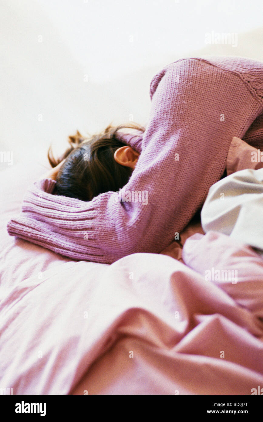 Woman lying on bed covering face with arm Stock Photo - Alamy