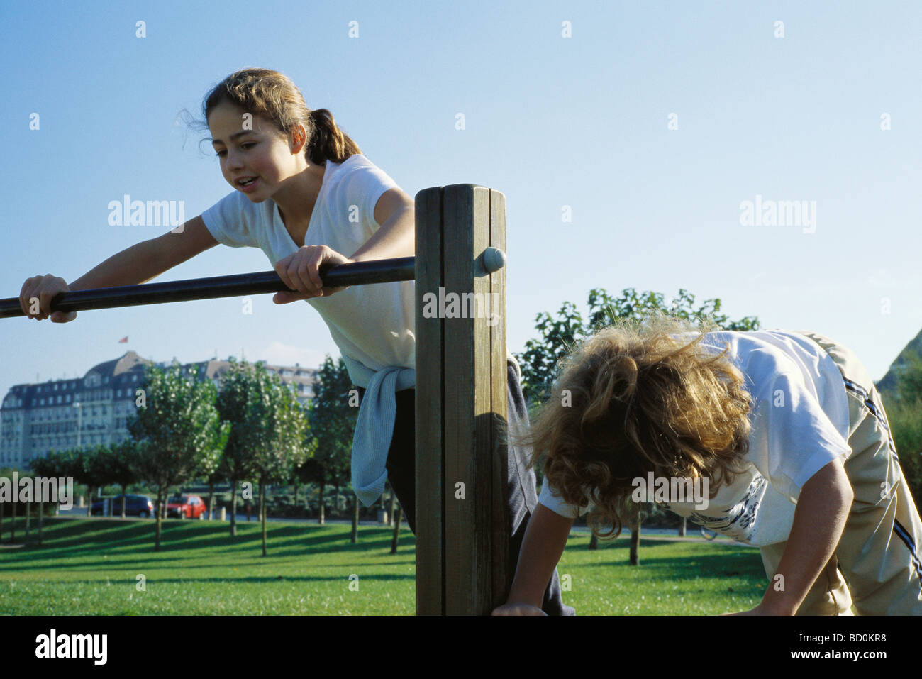 Girls playing on bars at park Stock Photo - Alamy
