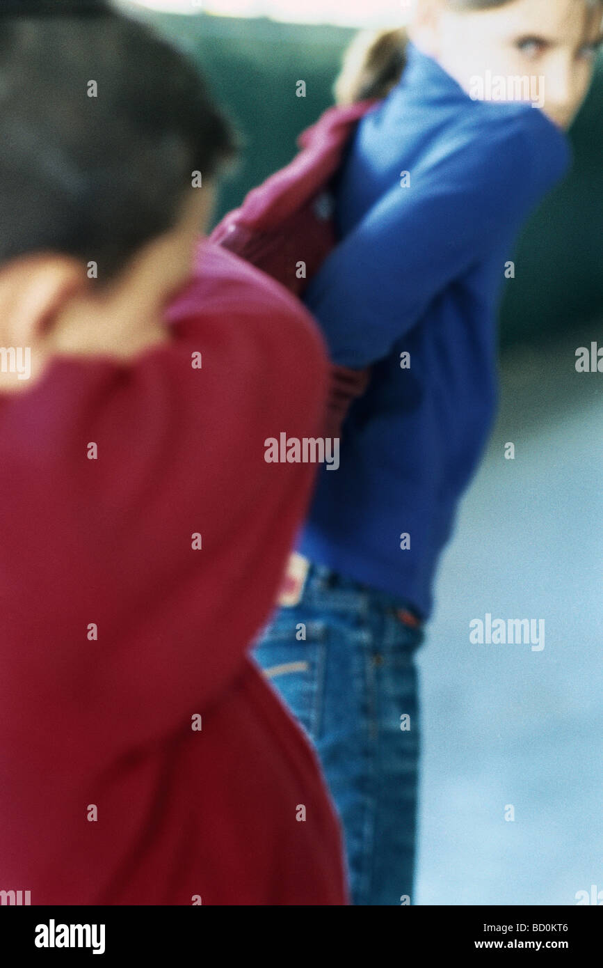 Boy covering his eyes crying, girl in background looking over shoulder ...