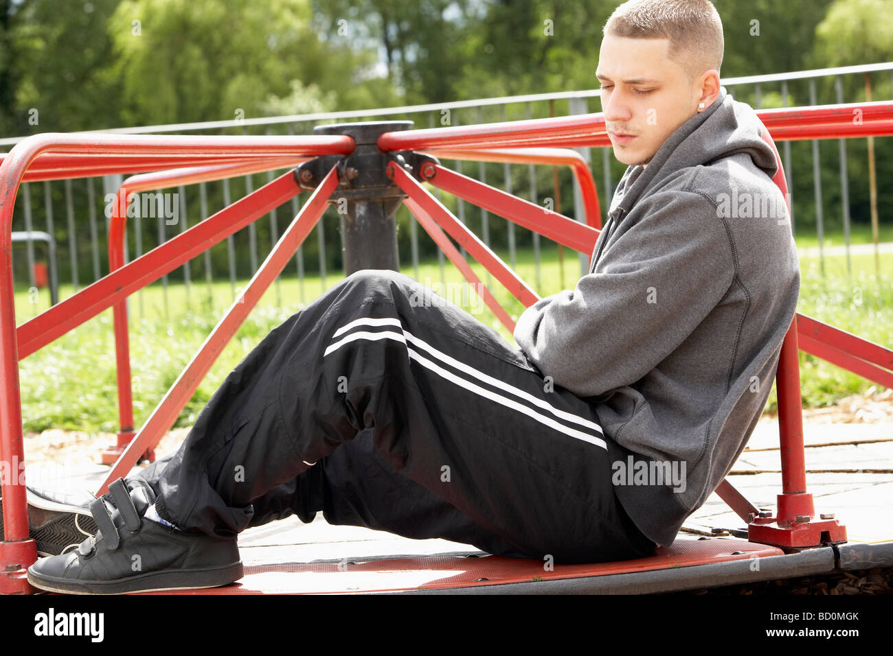 Young Man Sitting In Playground Stock Photo - Alamy