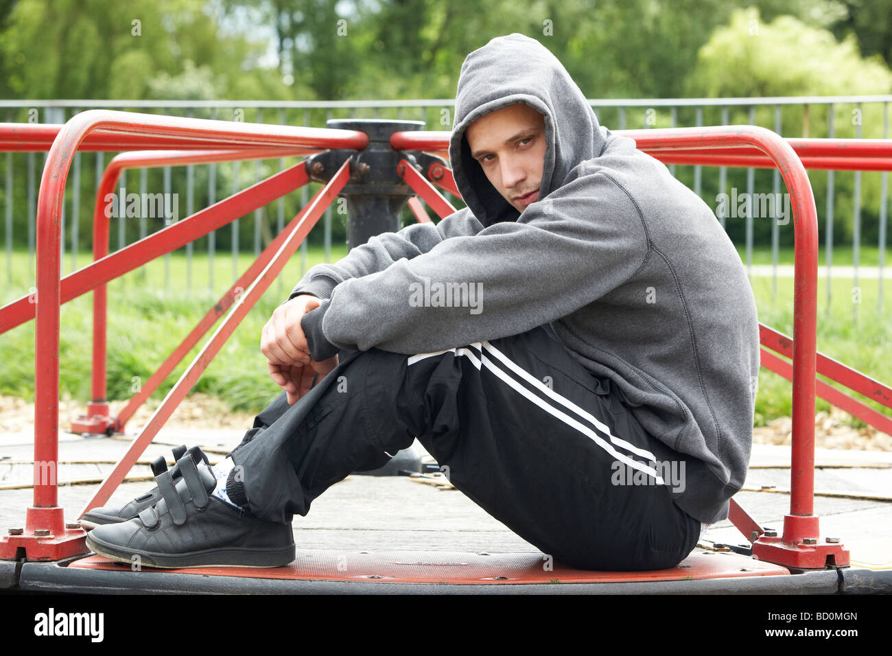 Young Man Sitting In Playground Stock Photo - Alamy