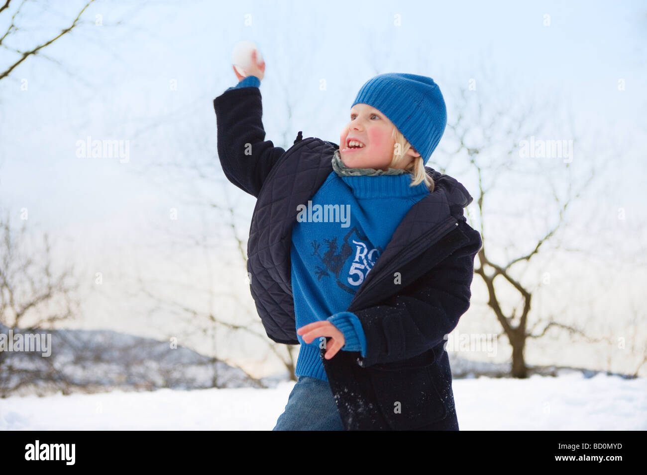 Scandinavian boy throwing snowball Stock Photo - Alamy