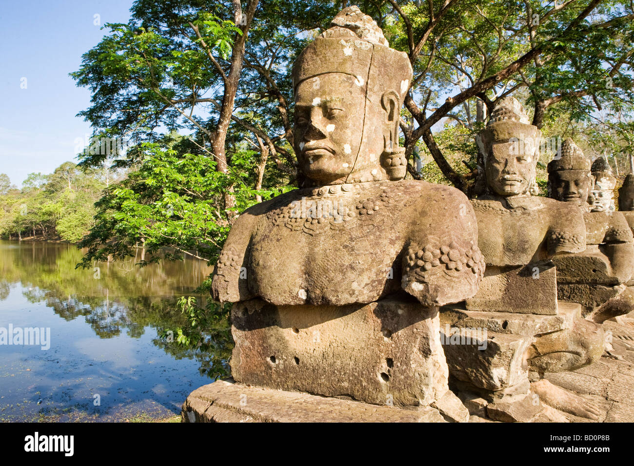 A line of stone statues leading up to a gateway to Angkor Thom in ...