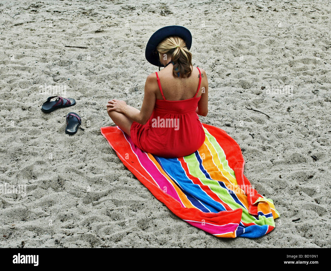 women on bright beach towel on sandy surface with shoes off and viewed ...