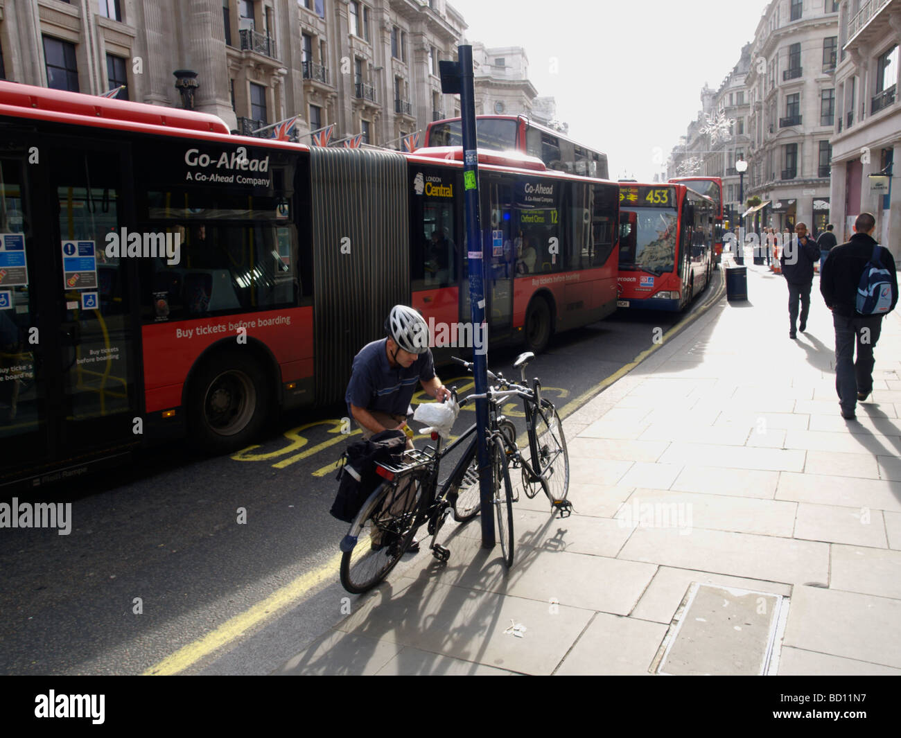 Bicyclist unpacking his bike in London s Regent Street with buses in the background London UK ...