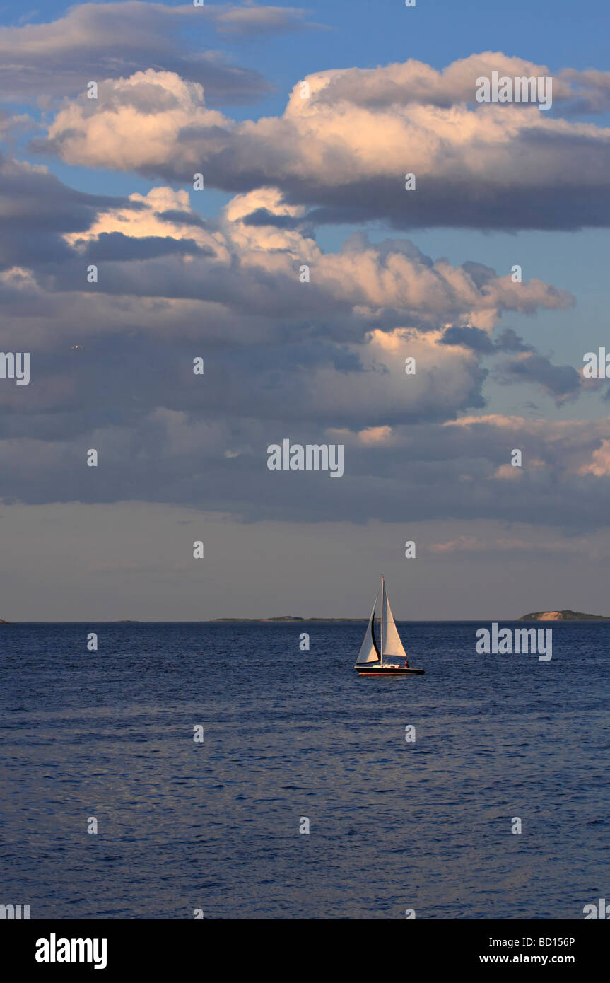 Single Sailboat on Atlantic Ocean with clouds in the sky and islands in ...