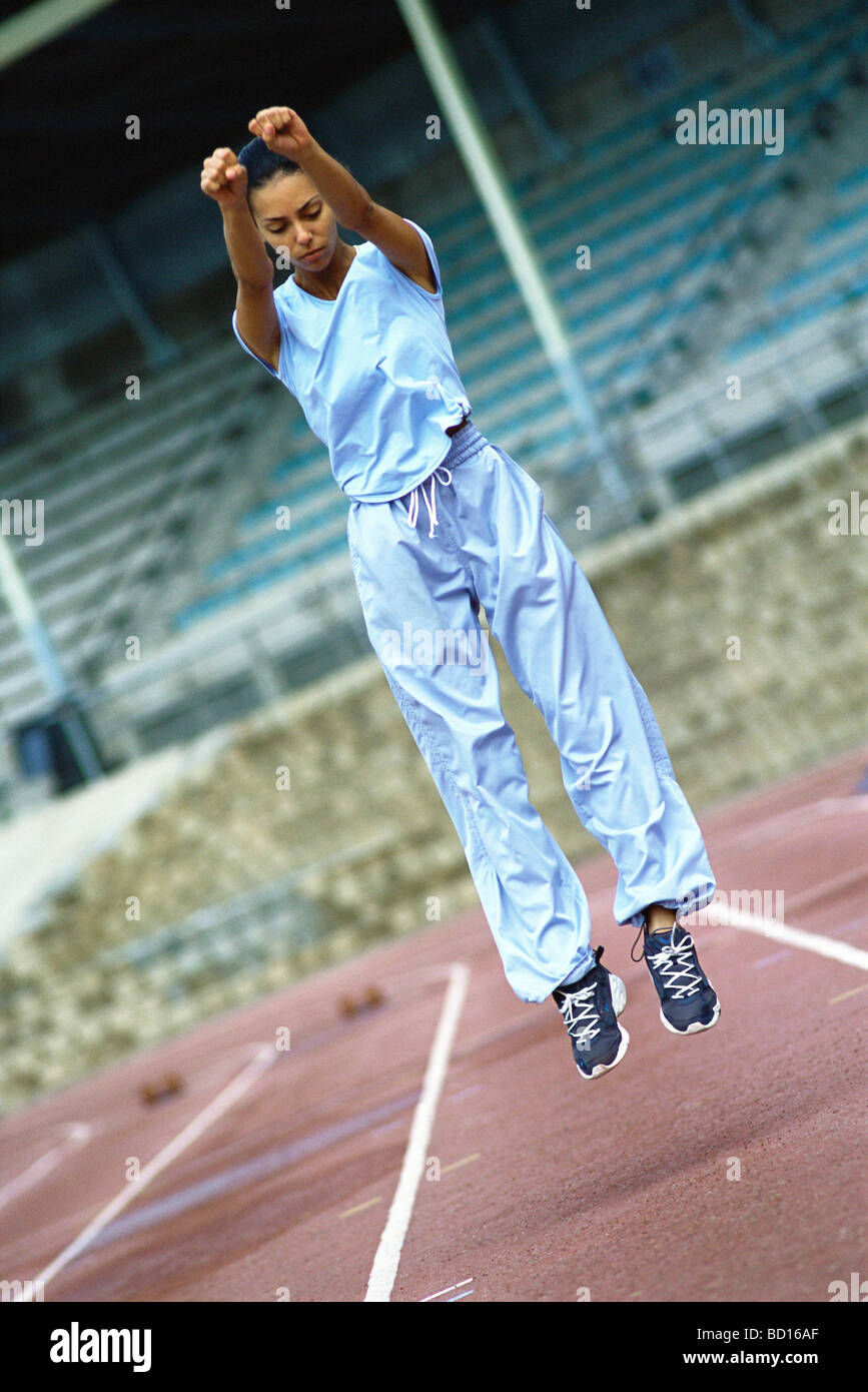 Young woman doing jumping exercises on track Stock Photo - Alamy