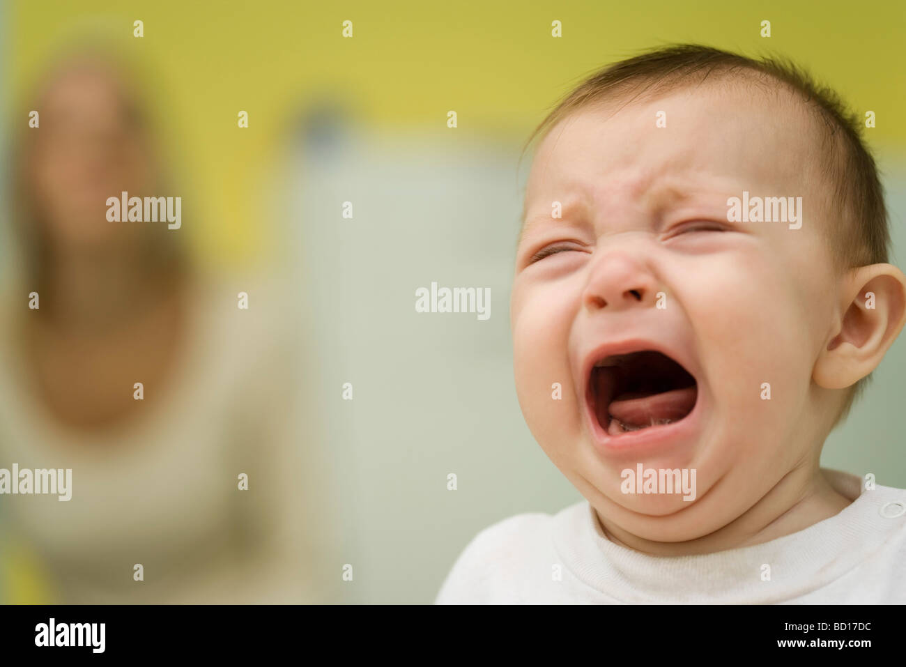 Baby crying, mother in background Stock Photo - Alamy