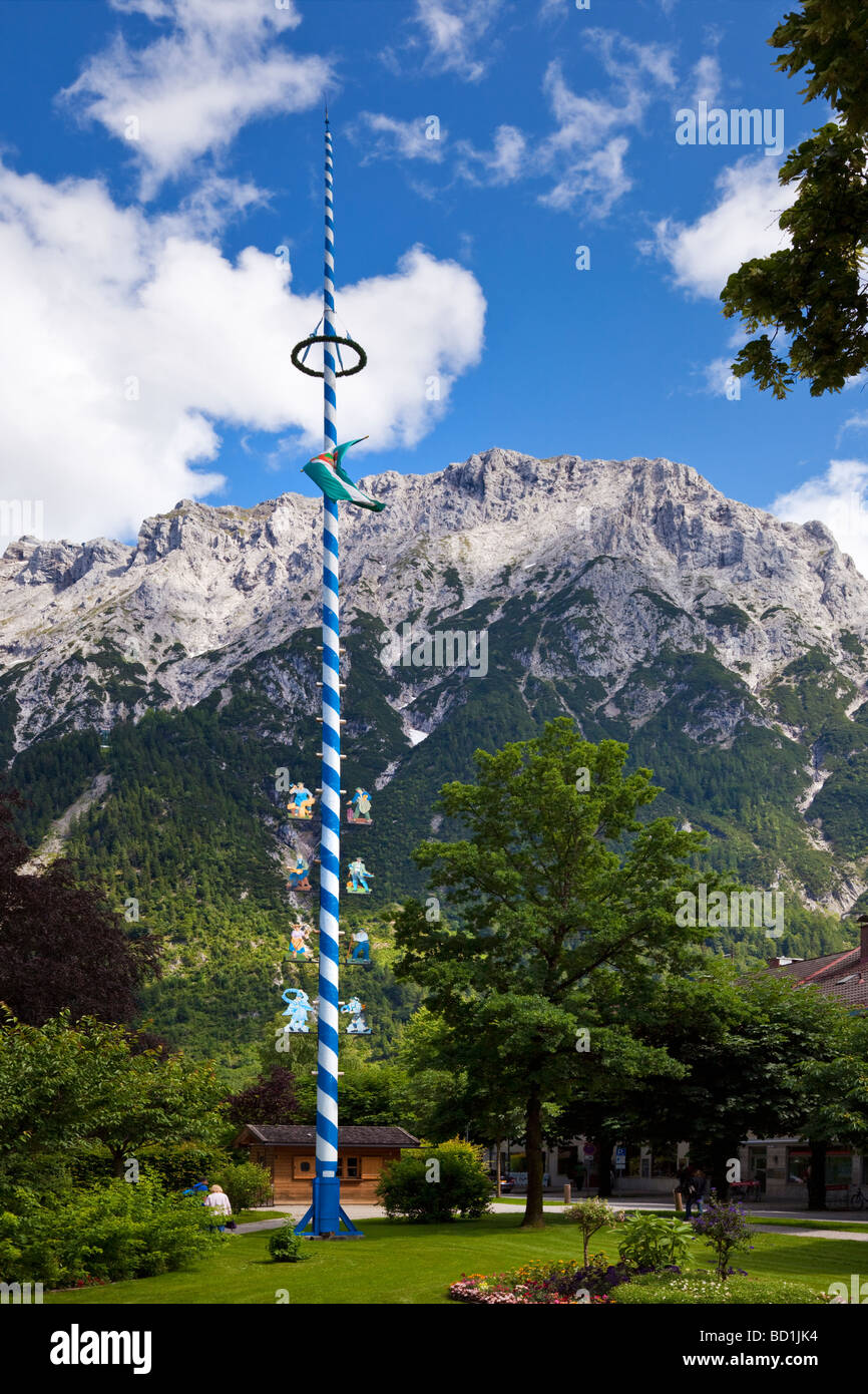 A traditional German maypole with trade symbols with mountains behind ...