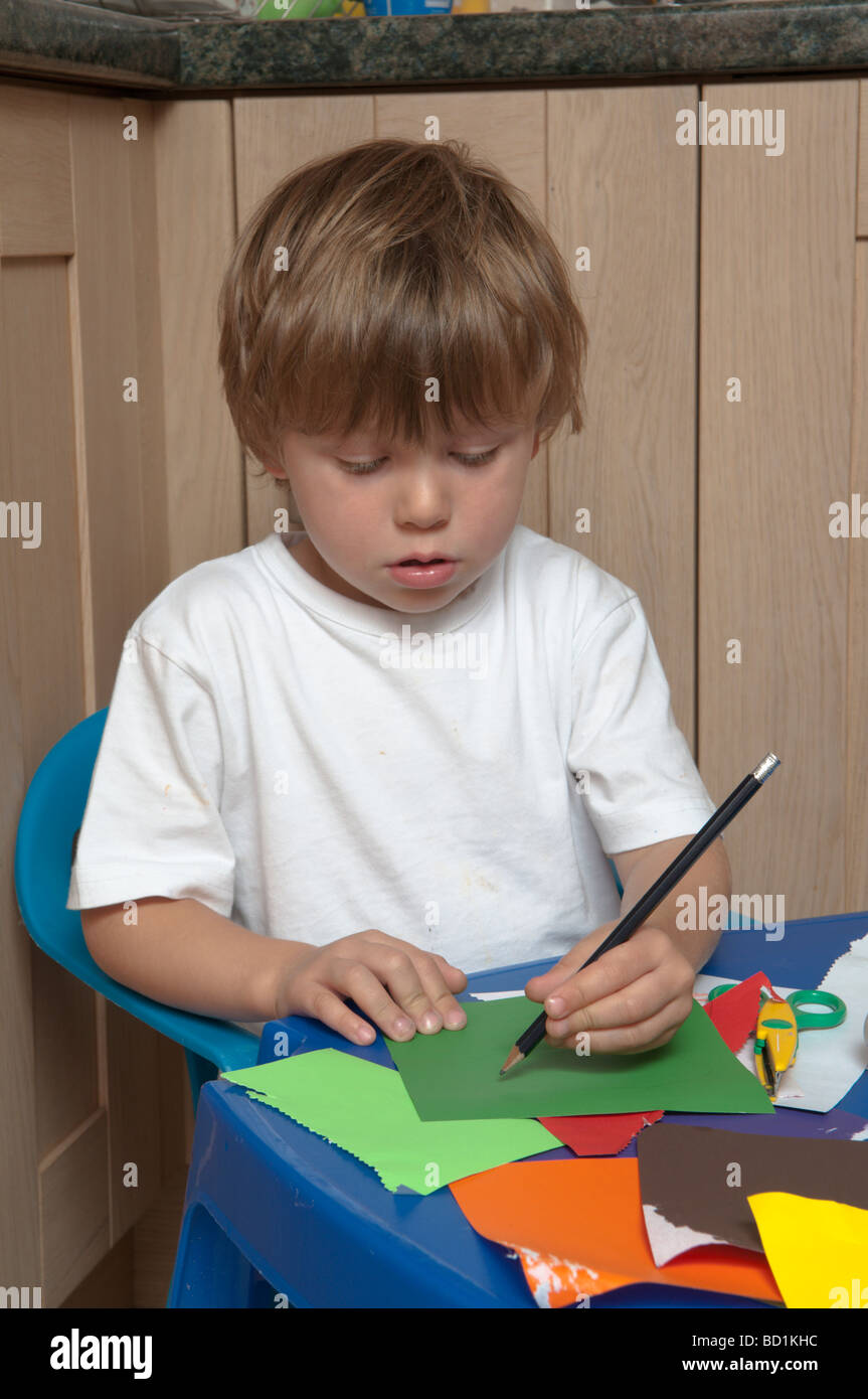 little boy at small table in kitchen learning how to use a pencil for ...