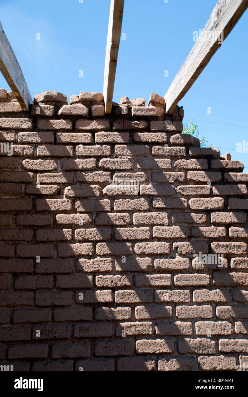 Underneath a brilliant blue sky, stands a crumbling adobe wall in ...