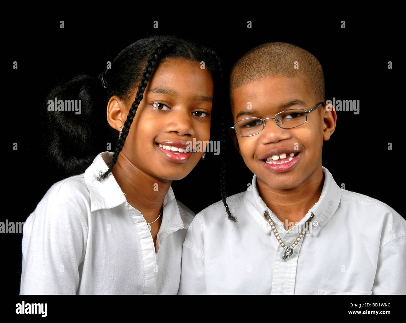 African American sister and brother smiling over a black background ...