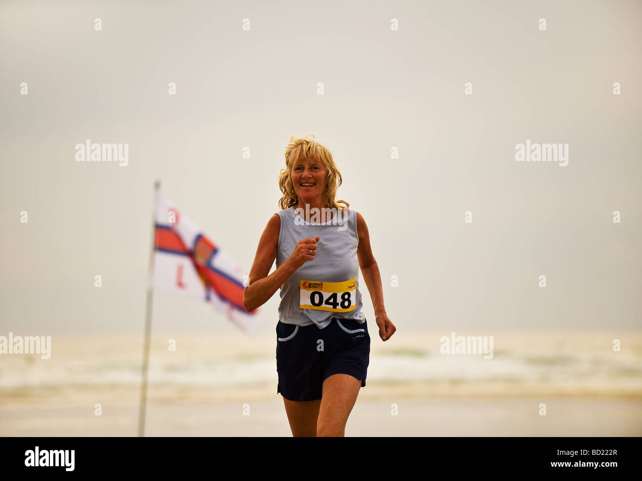 A woman running in a race on Gwithian Towans beach in Cornwall Stock ...