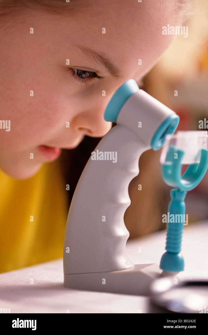 Young girl looking into microscope while taking notes at school Bothell ...