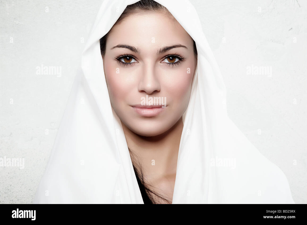 Portrait of a young woman wrapped in white cloth, looking directly ...