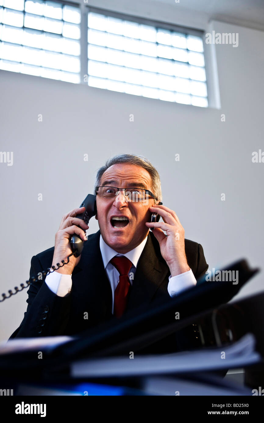 Manager with glasses and suit sitting in front of a mountain of folders ...
