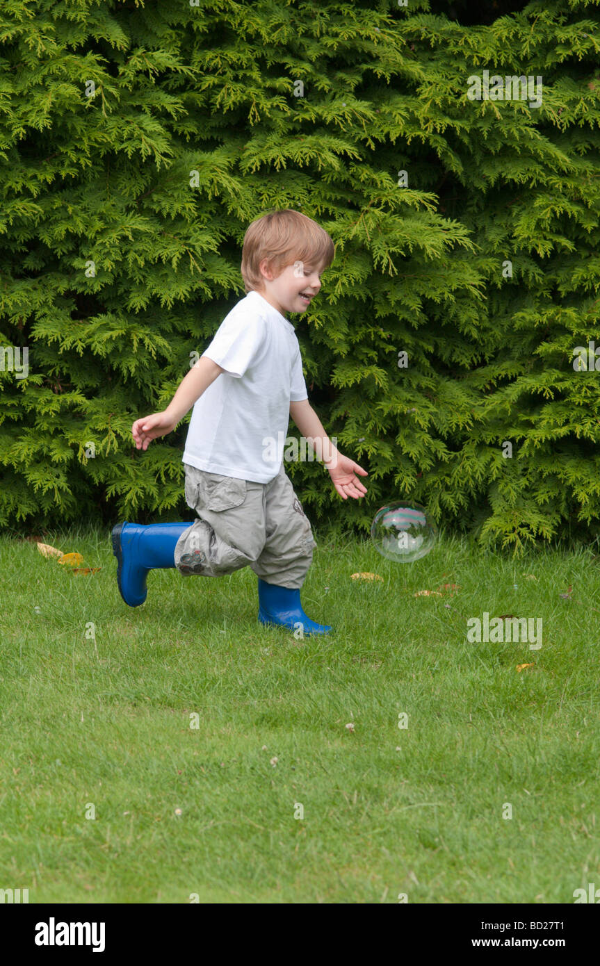 little boy chasing bubbles in garden, running and having fun, three ...