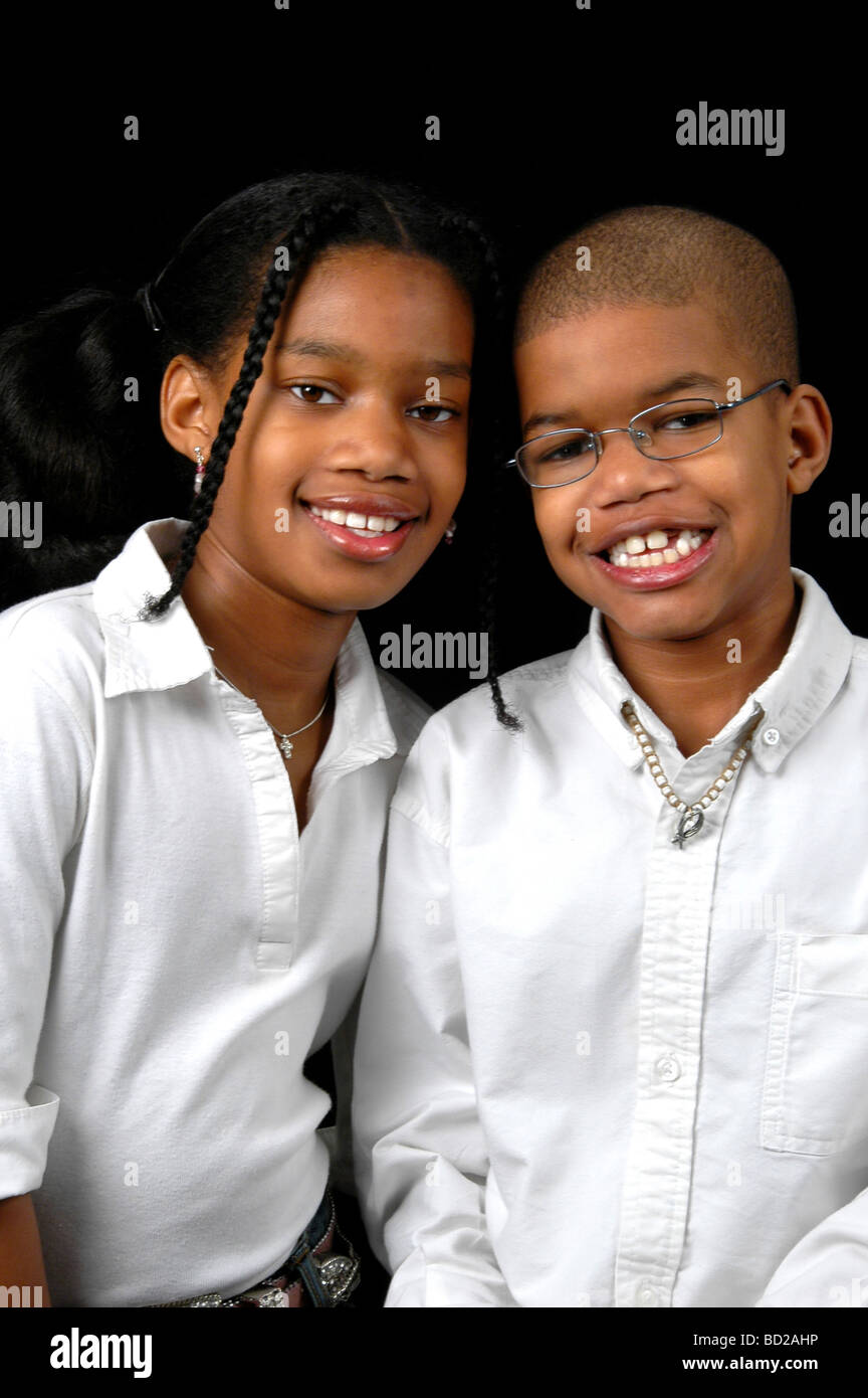 African American sister and brother in a vertical portrait over a black ...