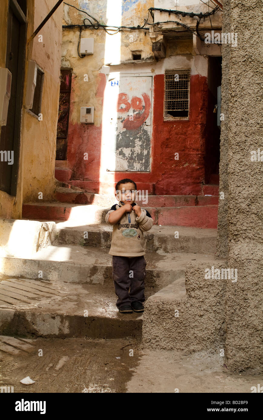 Little boy in a street in Tangier and the word boy written on the wall ...