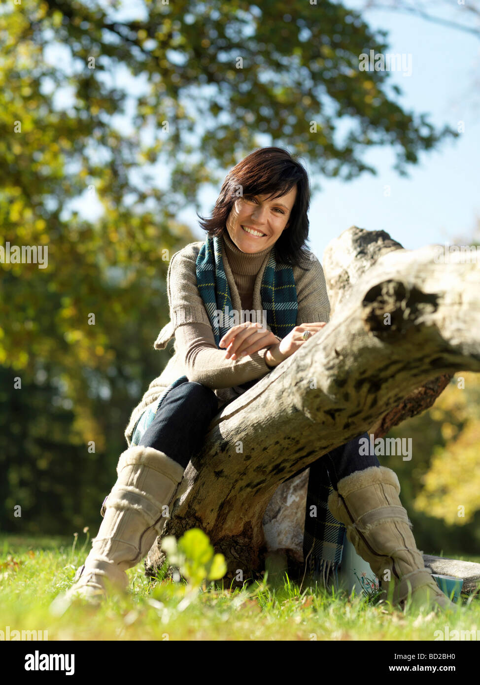 Woman sitting on log in Autumn Stock Photo - Alamy