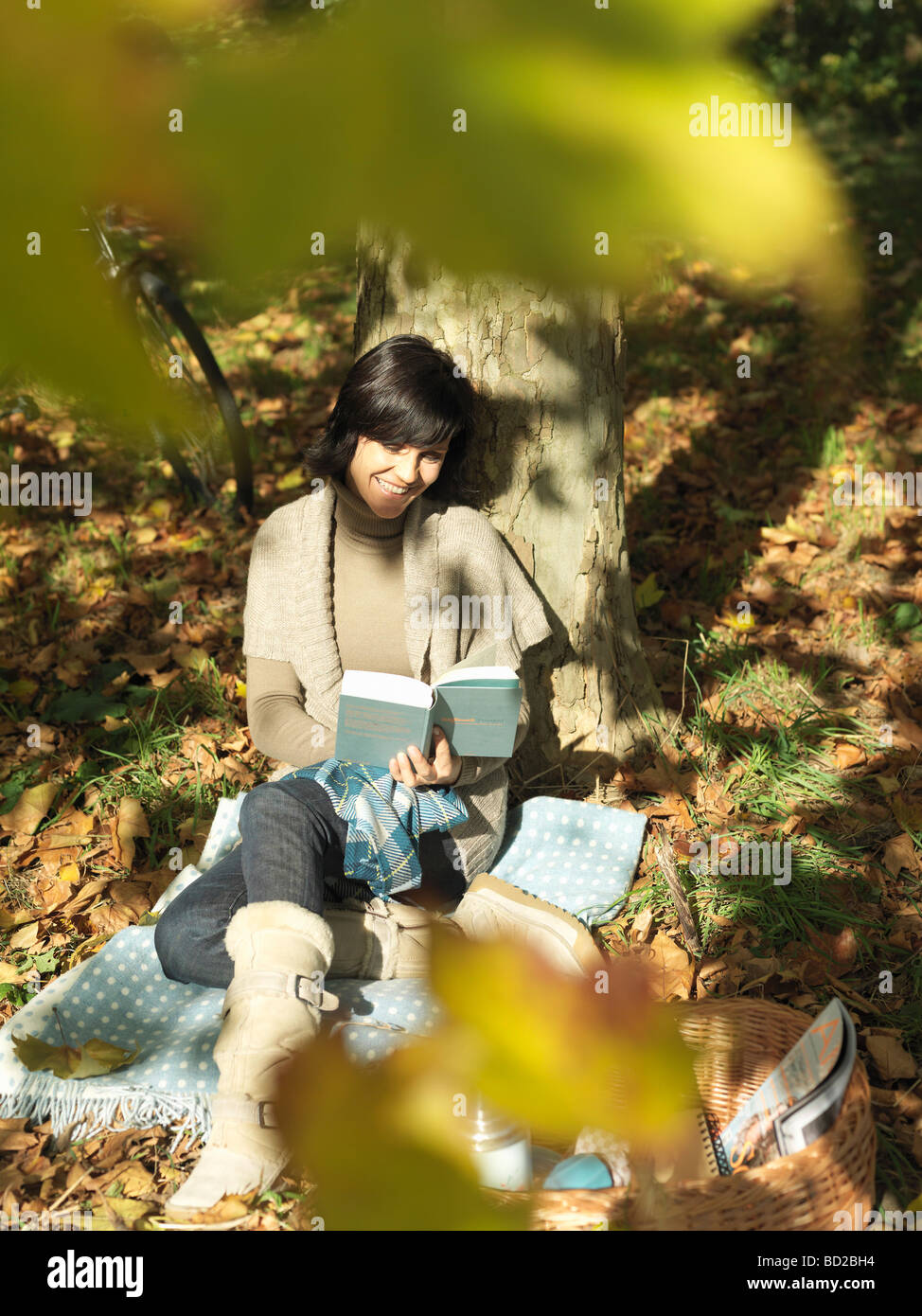 Woman reading under tree in Autumn Stock Photo - Alamy
