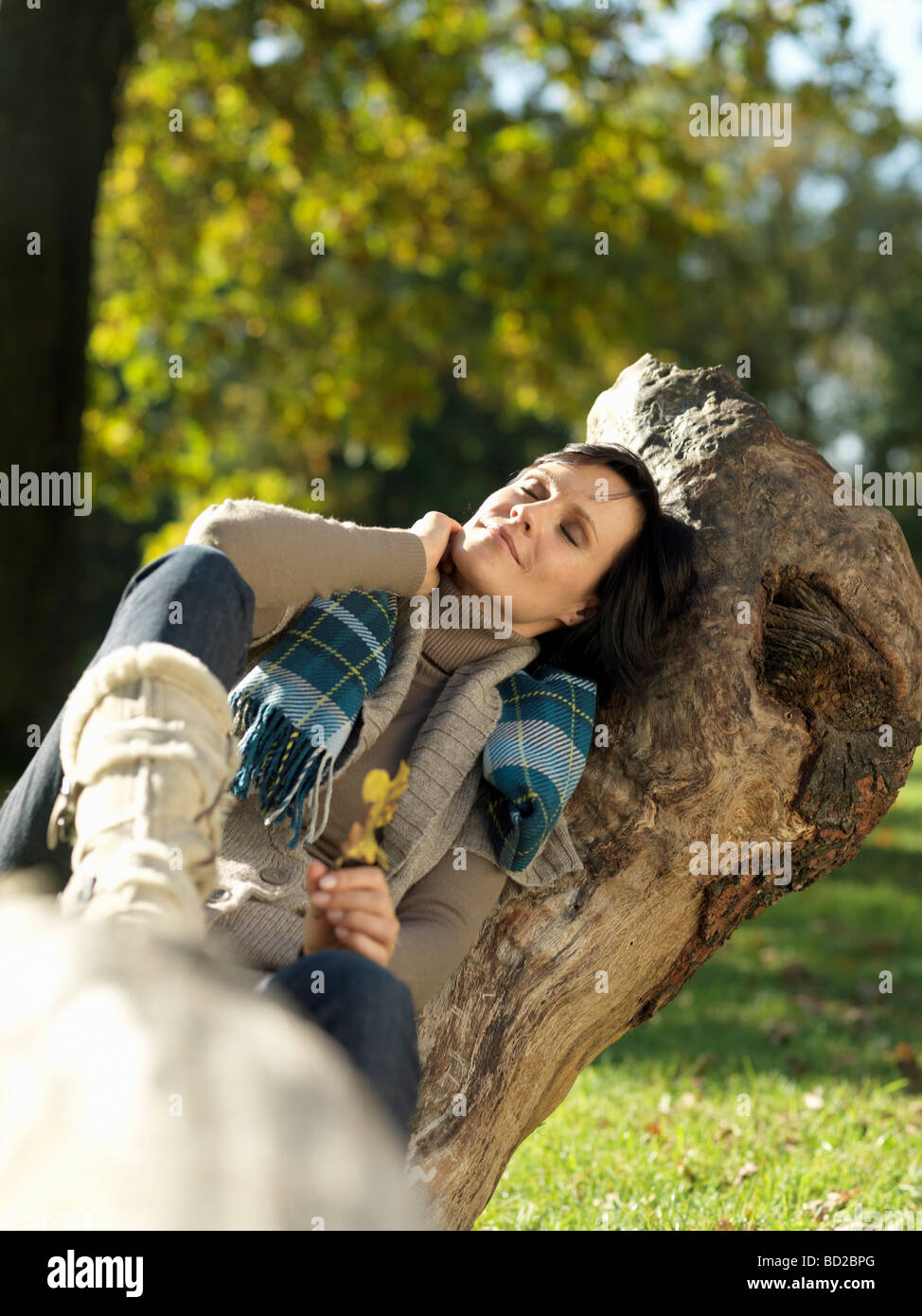 Woman leaning against tree in Autumn Stock Photo - Alamy