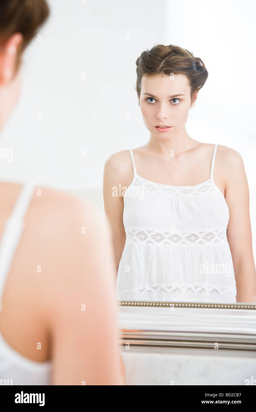 Woman looking in mirror Stock Photo - Alamy
