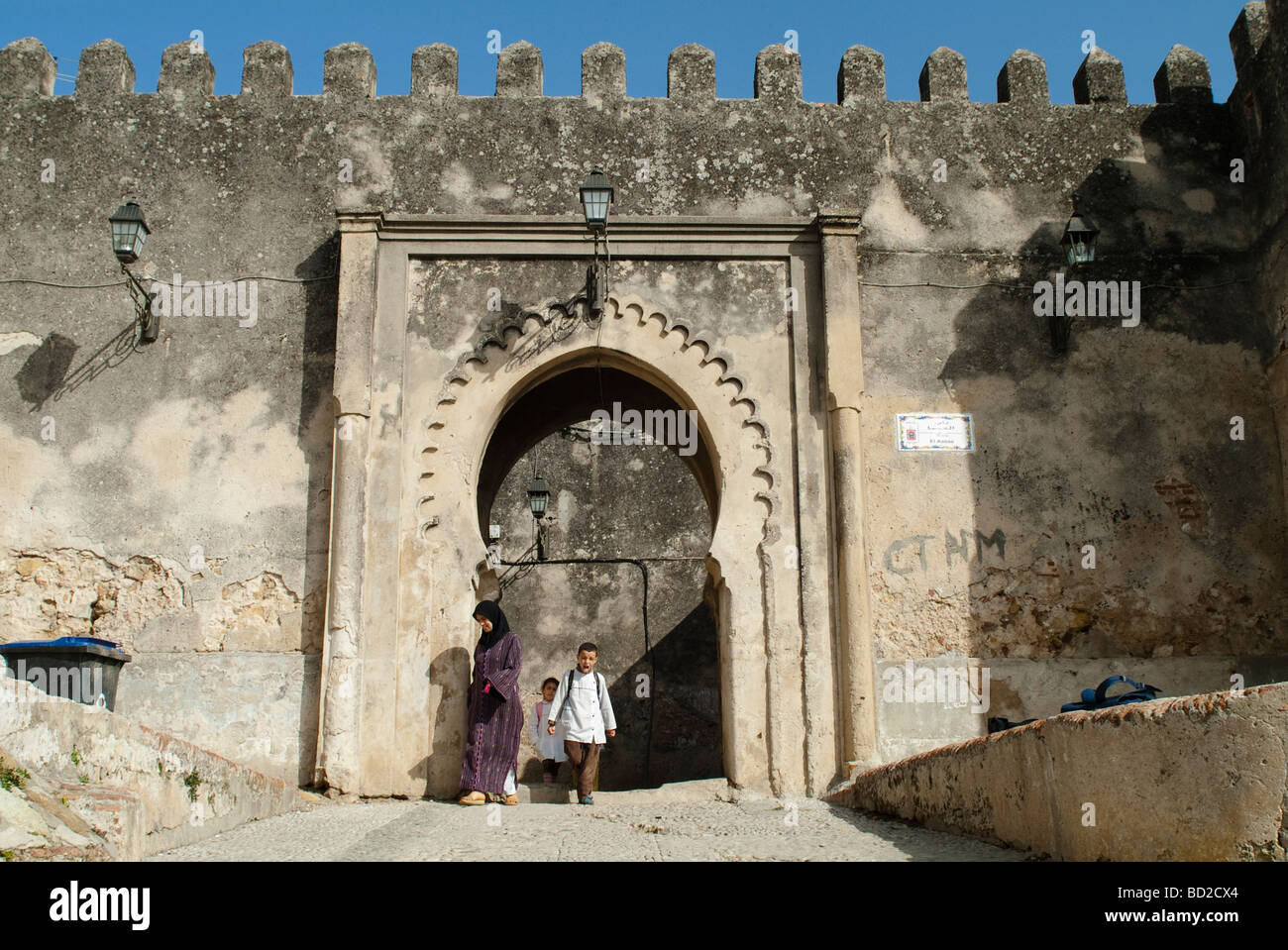 Mother and children walking through the gate in the old city walls ...