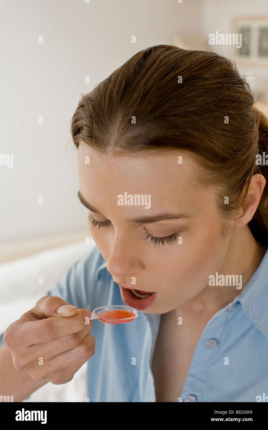 Sick woman taking syrup Stock Photo - Alamy