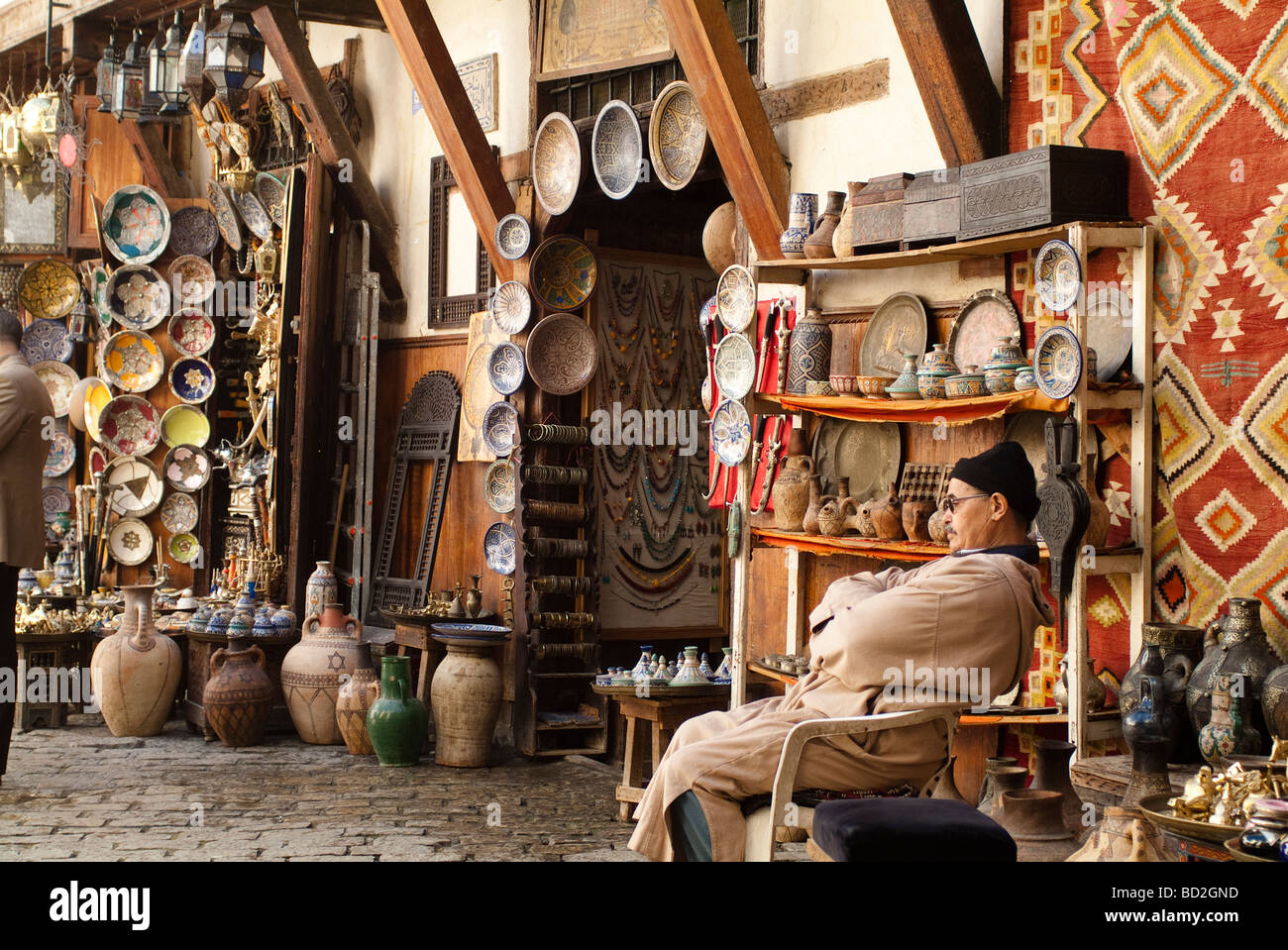 Shopkeeper sitting in front of his shop selling pottery ceramics and ...
