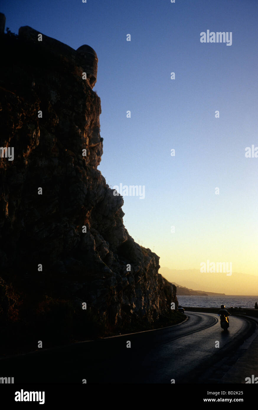 Moped rider driving around a cliff at dusk Stock Photo - Alamy