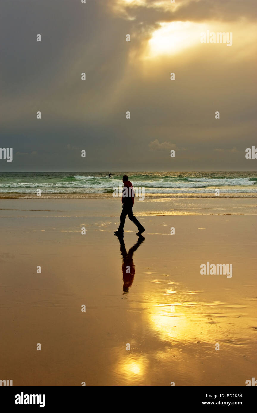 A man walking across a beach in Cornwall Stock Photo - Alamy