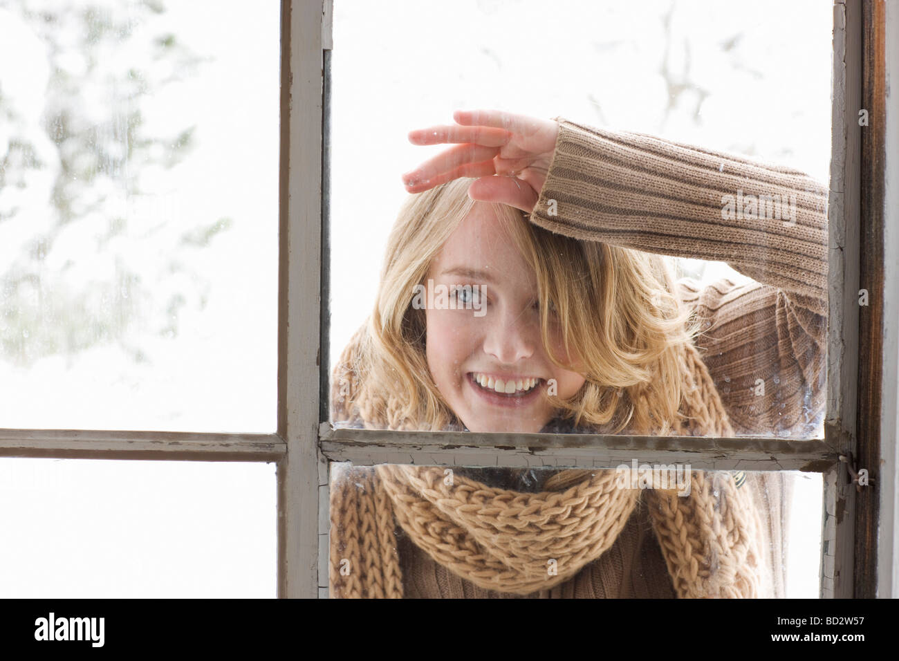 Young woman looking through window Stock Photo - Alamy
