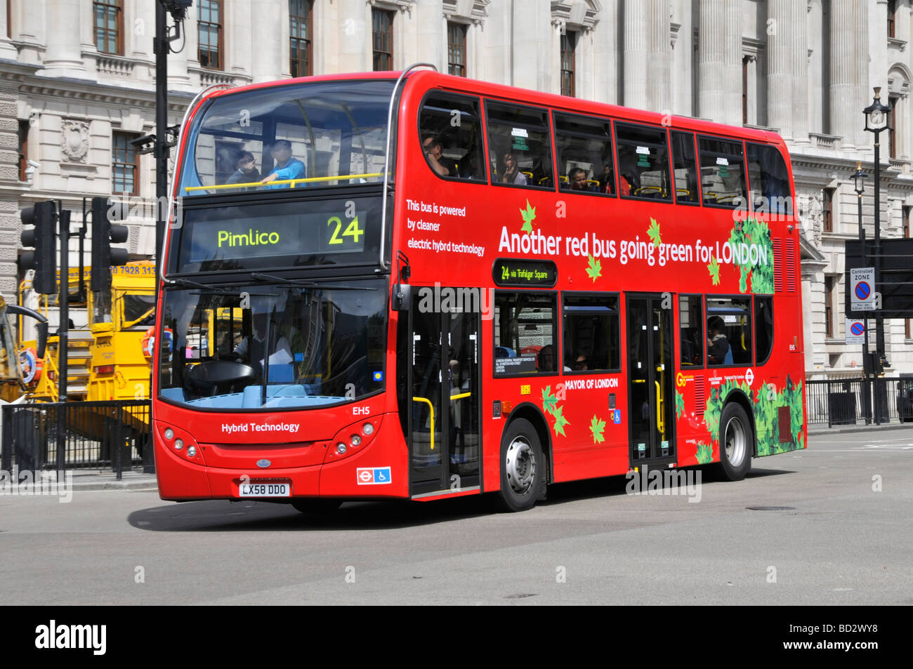 Side view of red double decker passenger bus going Green for public ...