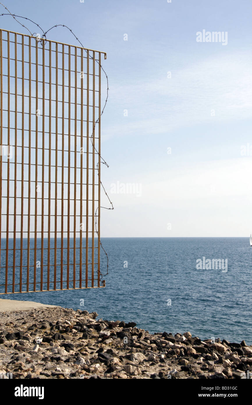 metal fence with barbed wire by blue sea Stock Photo - Alamy