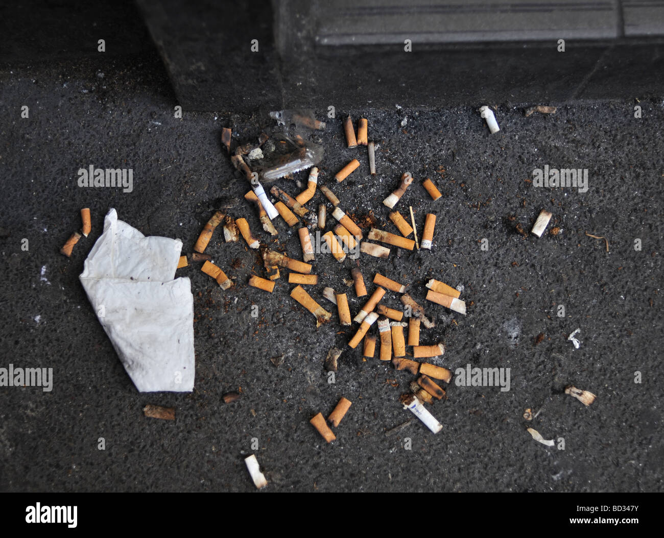 Dirty Cigarette ends stubbed out and left on a pavement Stock Photo - Alamy