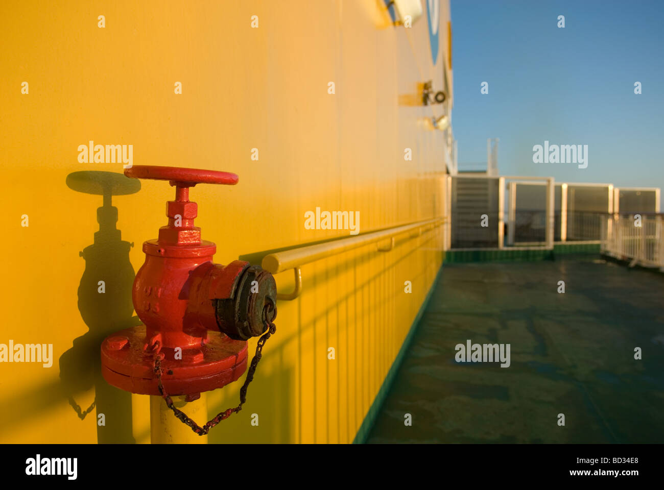 Red fire hydrant tap on ferry with yellow steel wall at sunset with ...
