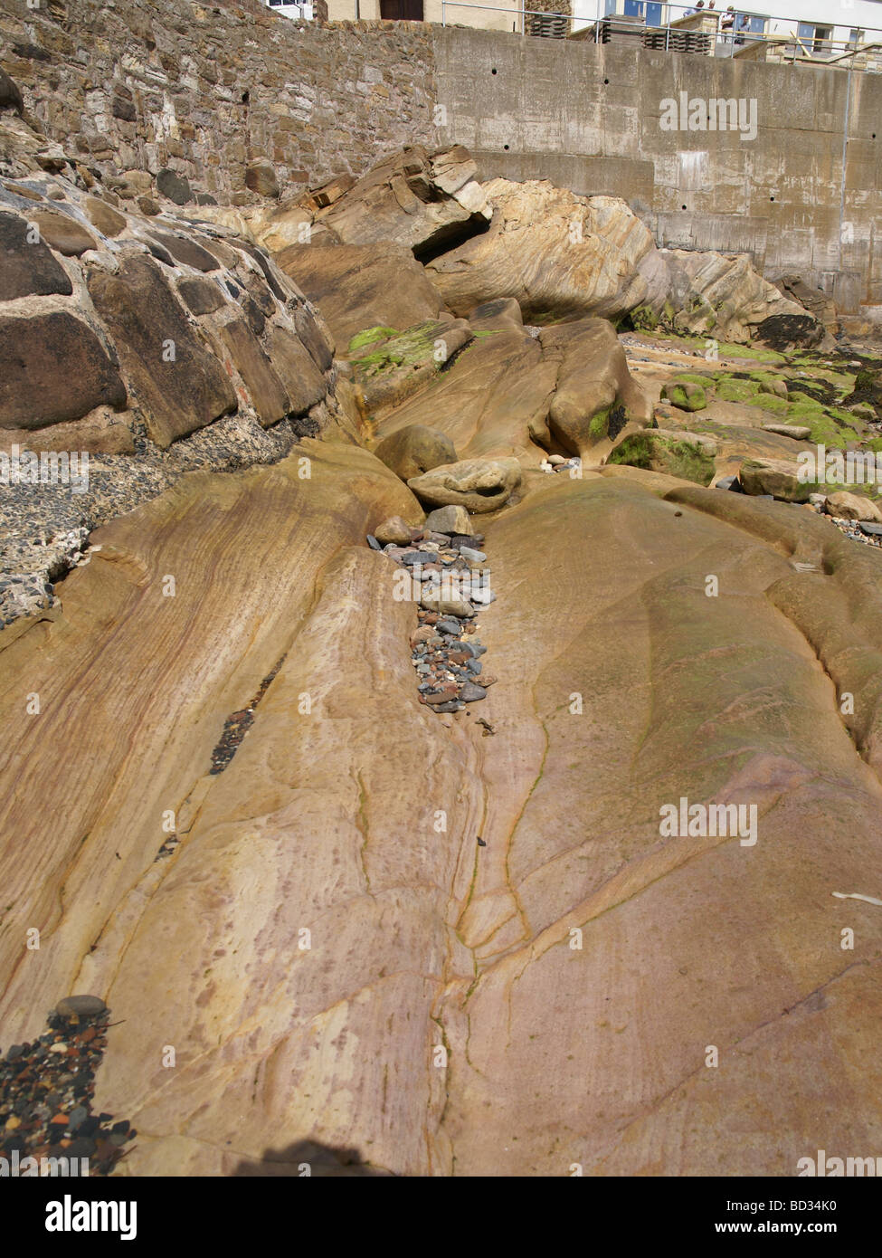 Colourful water worn stone pebbles captured in a rock gully at low tide ...