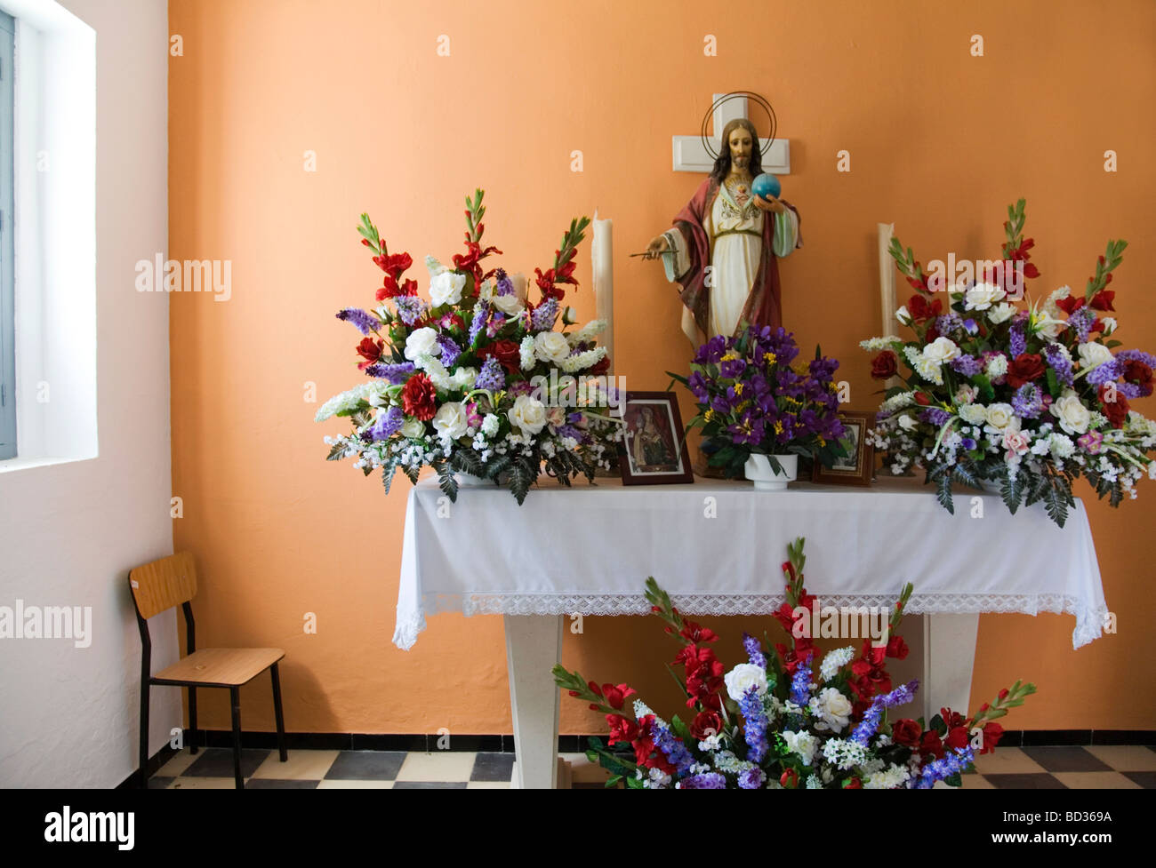 Inside small chapel at cemetery in Spain. Altar with flowers and statue ...