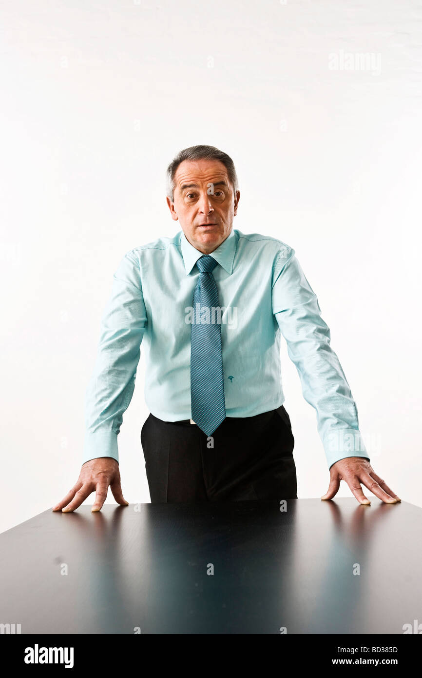 Manager leaning on his desk with a skeptical expression Stock Photo - Alamy
