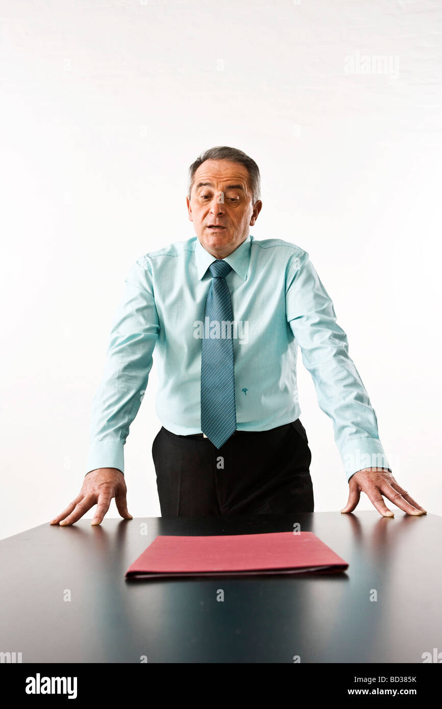 Manager leaning on his desk with a skeptical expression Stock Photo - Alamy