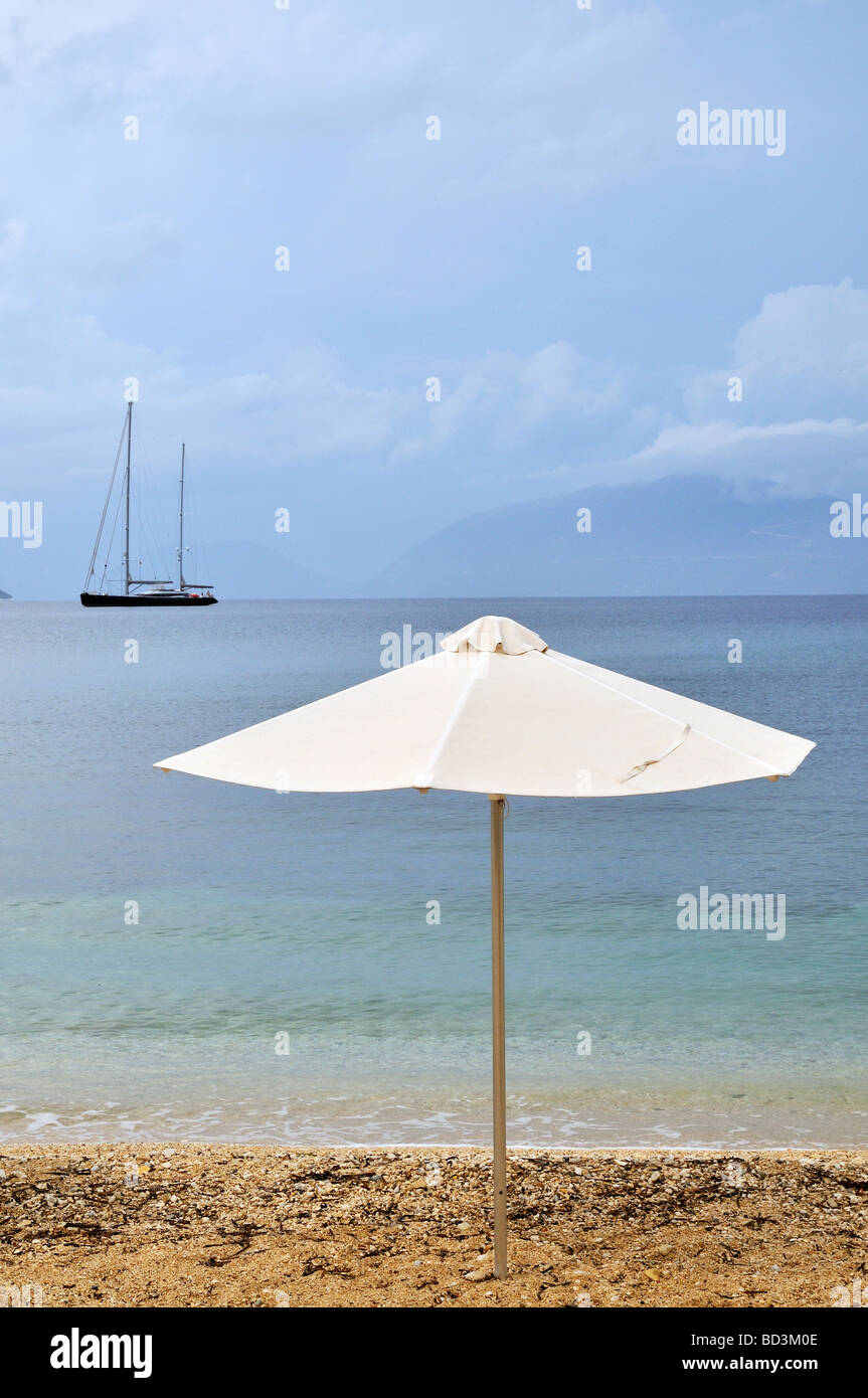 Beach with parasol and sailboat in the sea Stock Photo - Alamy