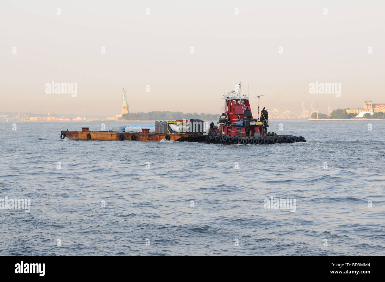 On a summer morning, a tugboat pushes a barge through New York harbor ...
