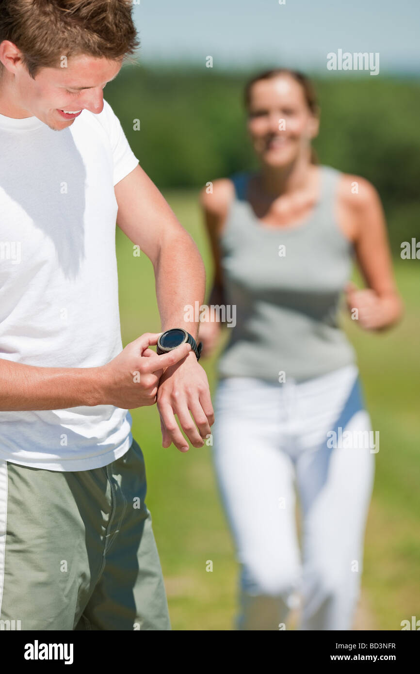 Jogging - Young man with stopwatch measuring time running woman in ...