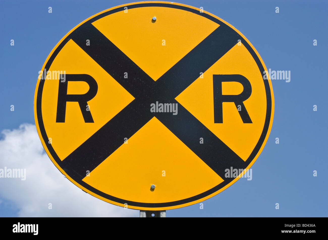 Yellow circular RR RXR railroad crossing warning sign against a blue ...