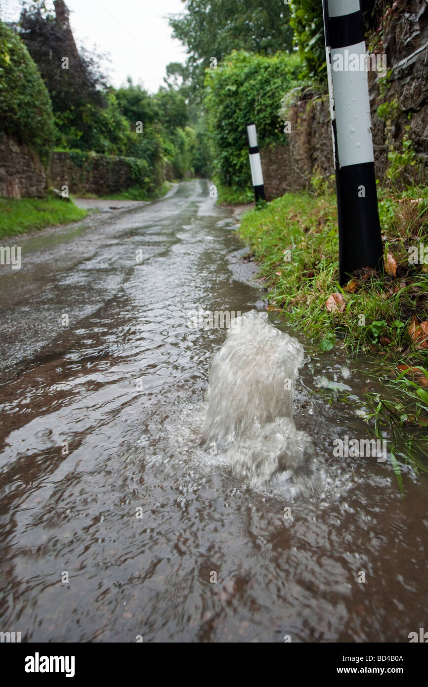 Water gushing out of drain and water running down country lane after ...